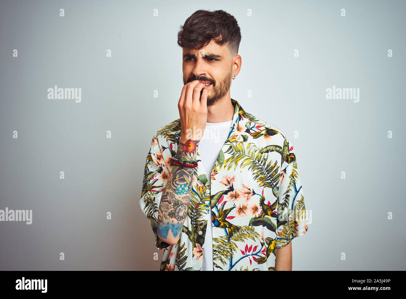 Man with tattoo on vacation wearing summer shirt standing over isolated ...
