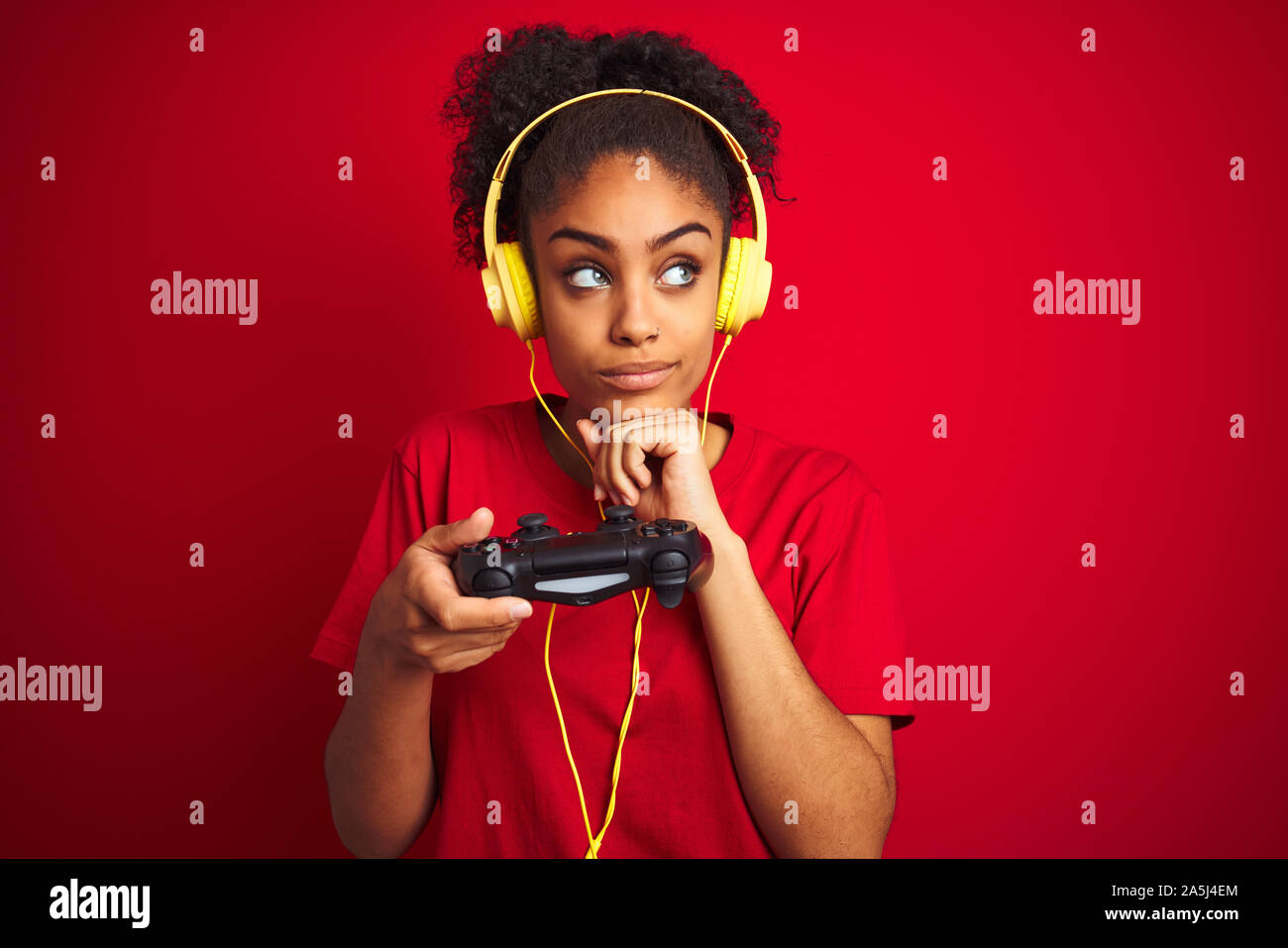 Afro woman playing video game using joystick and headphones over ...
