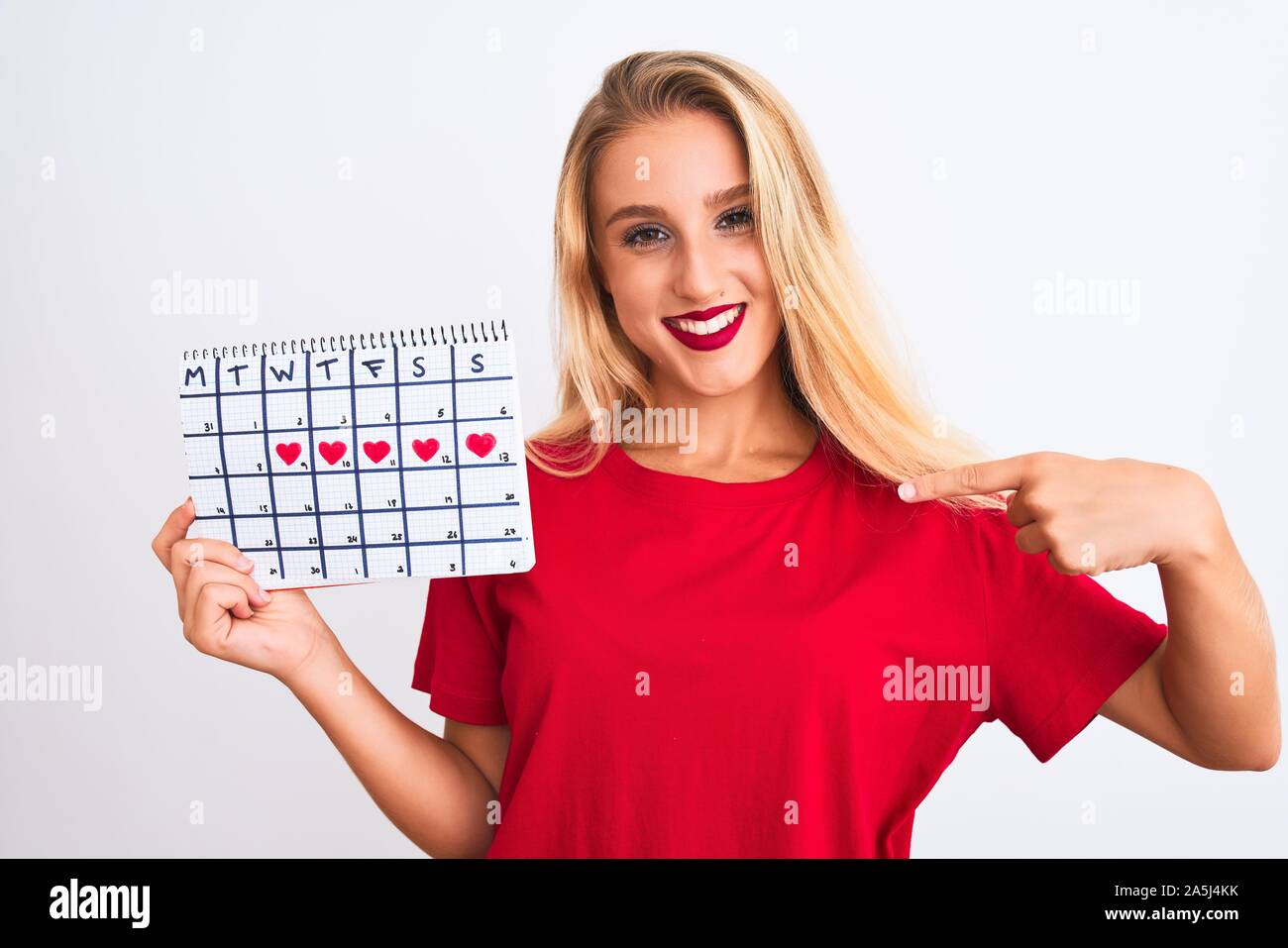 Young beautiful woman holding period calendar standing over isolated ...