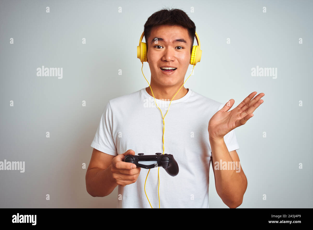Young asian chinese gamer man playing video game standing over isolated ...