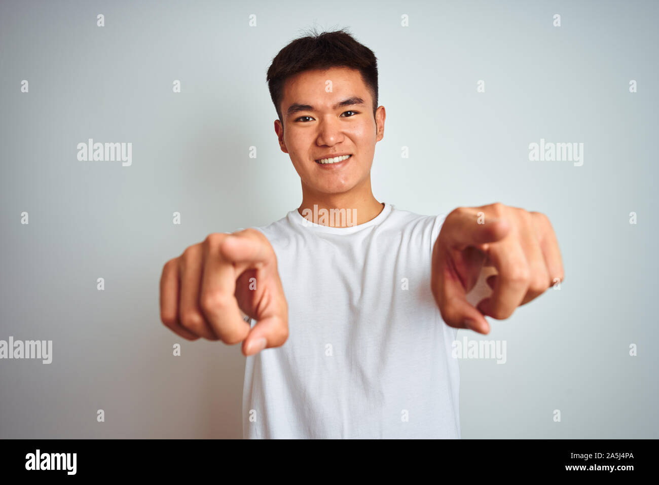 Young asian chinese man wearing t-shirt standing over isolated white ...