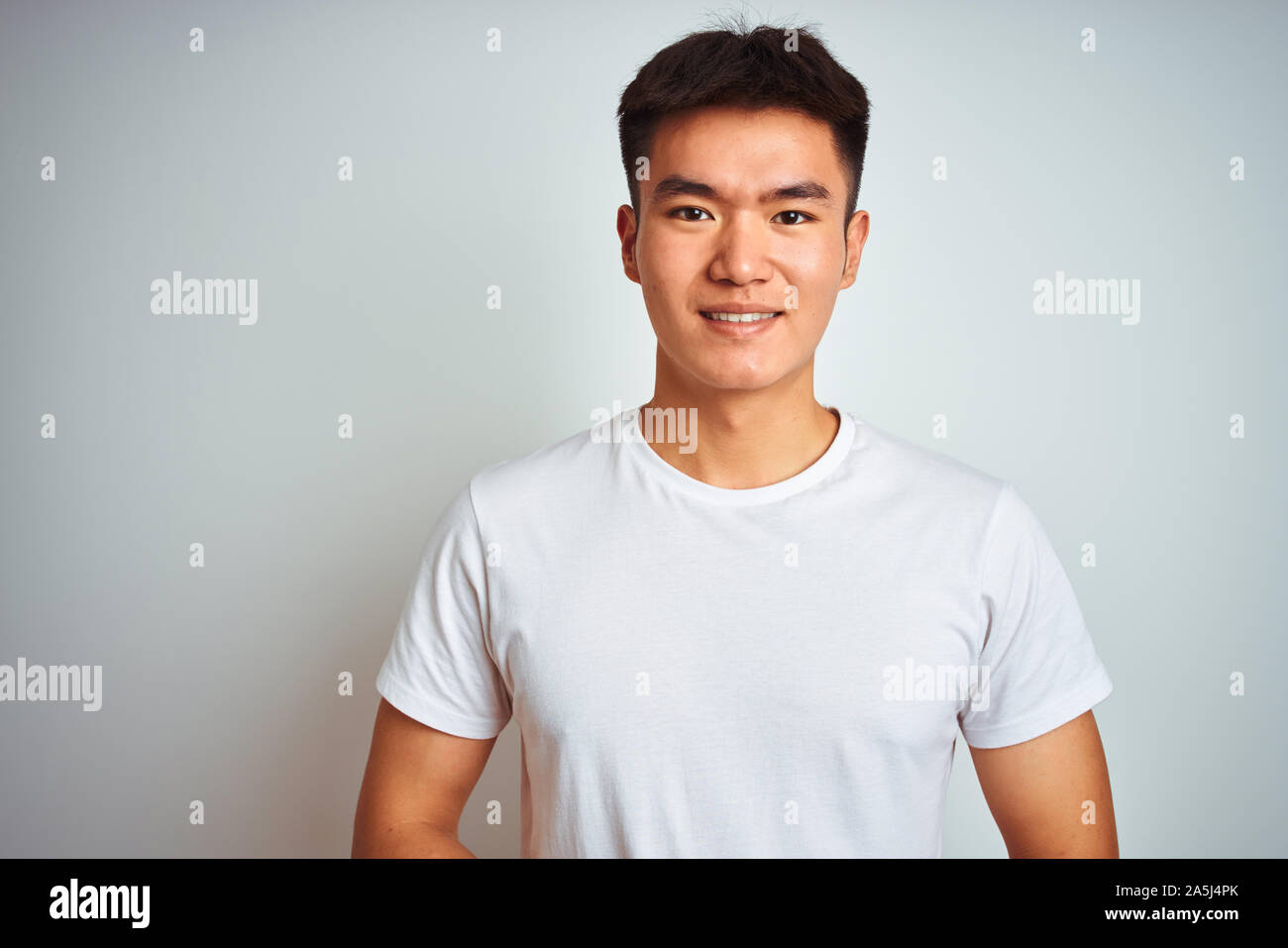 Young asian chinese man wearing t-shirt standing over isolated white ...
