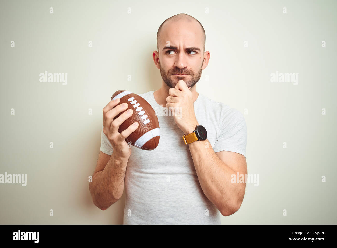 Young man holding rugby american football ball over isolated background ...