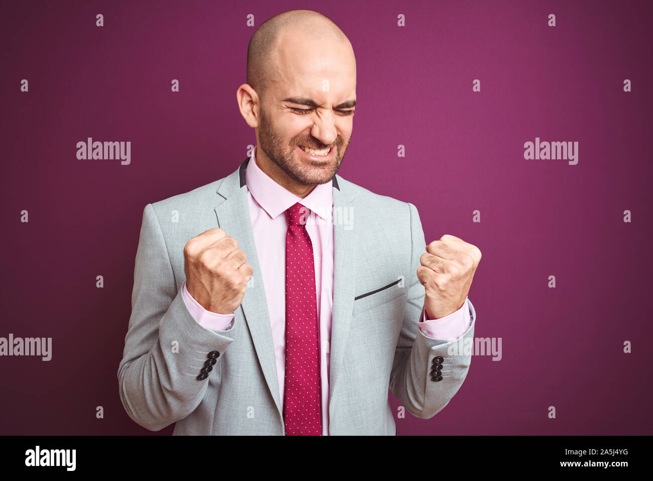 Young business man wearing suit and tie over purple isolated background ...