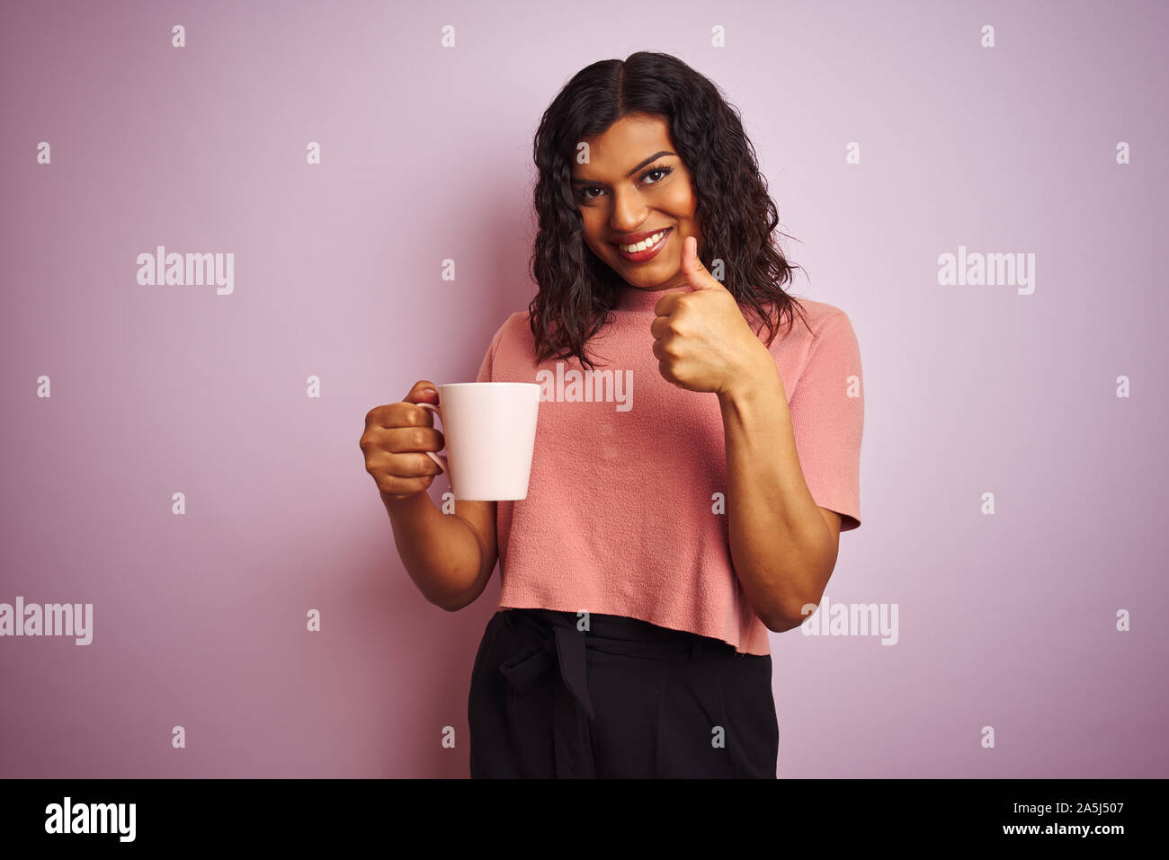 Transsexual transgender woman drinking cup of coffee over isolated pink ...