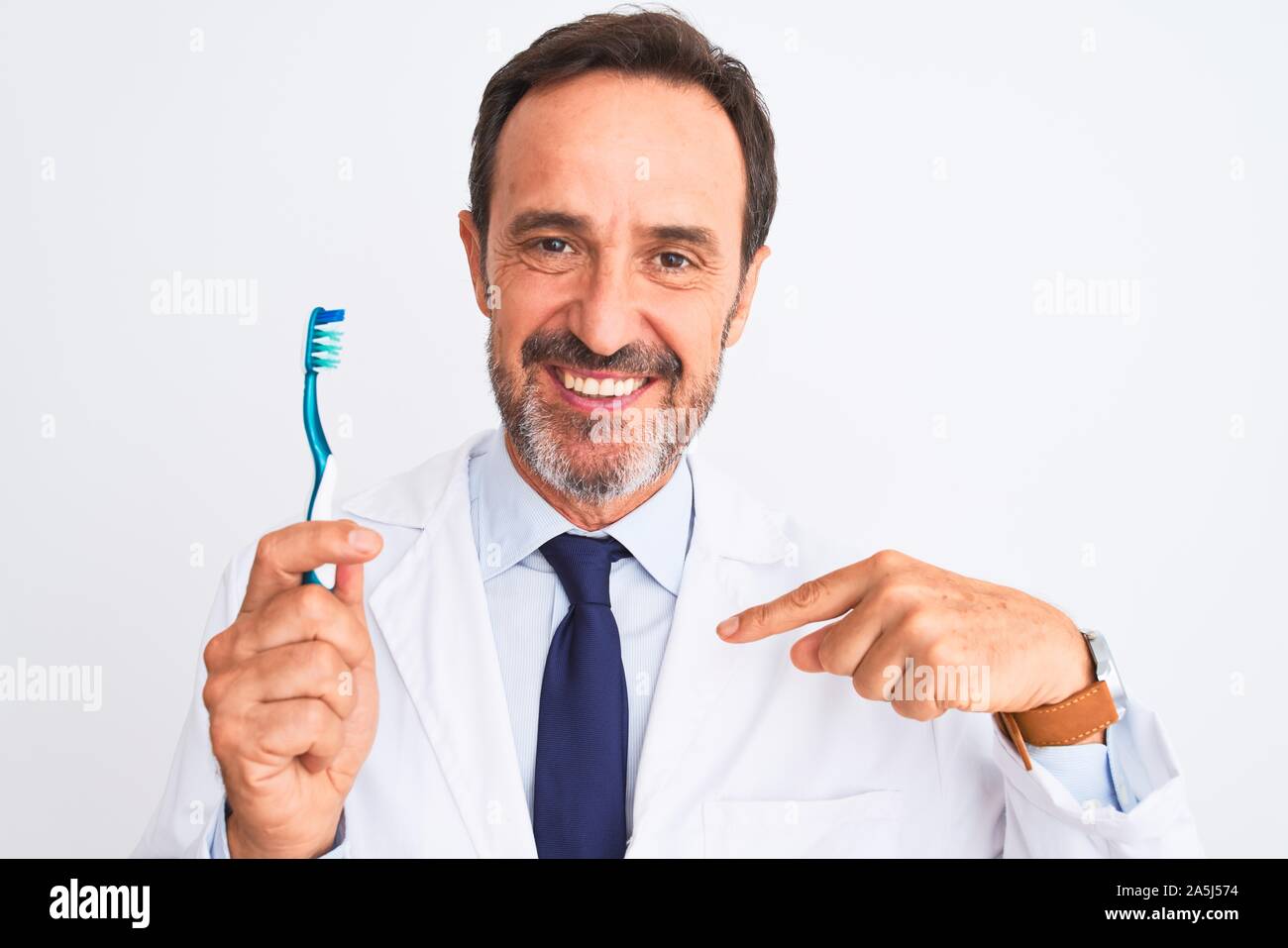 Middle age dentist man holding toothbrush standing over isolated white ...