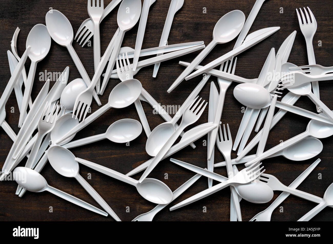 Plastic disposable tableware scattered on wooden table, top view Stock ...