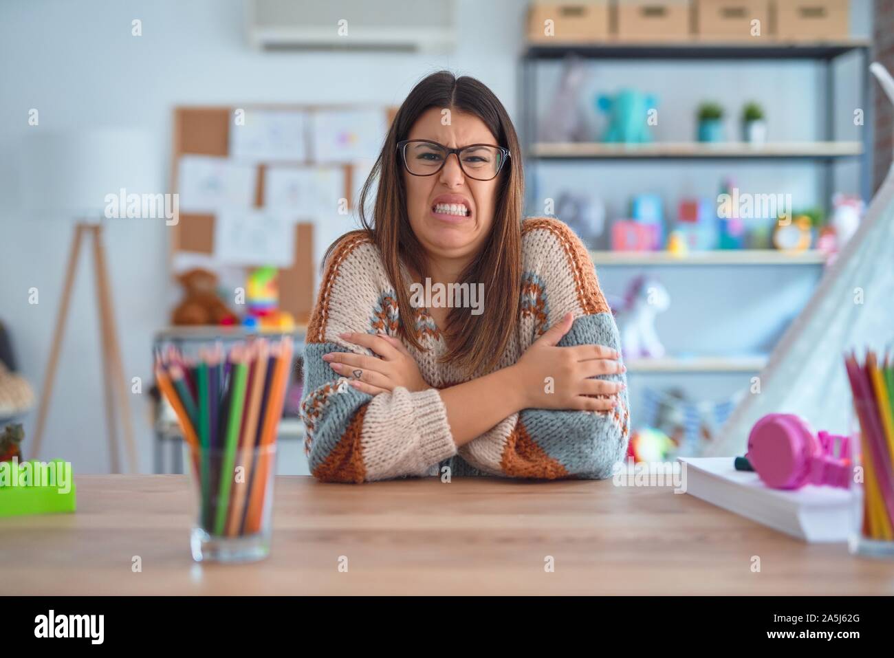 Young beautiful teacher woman wearing sweater and glasses sitting on ...
