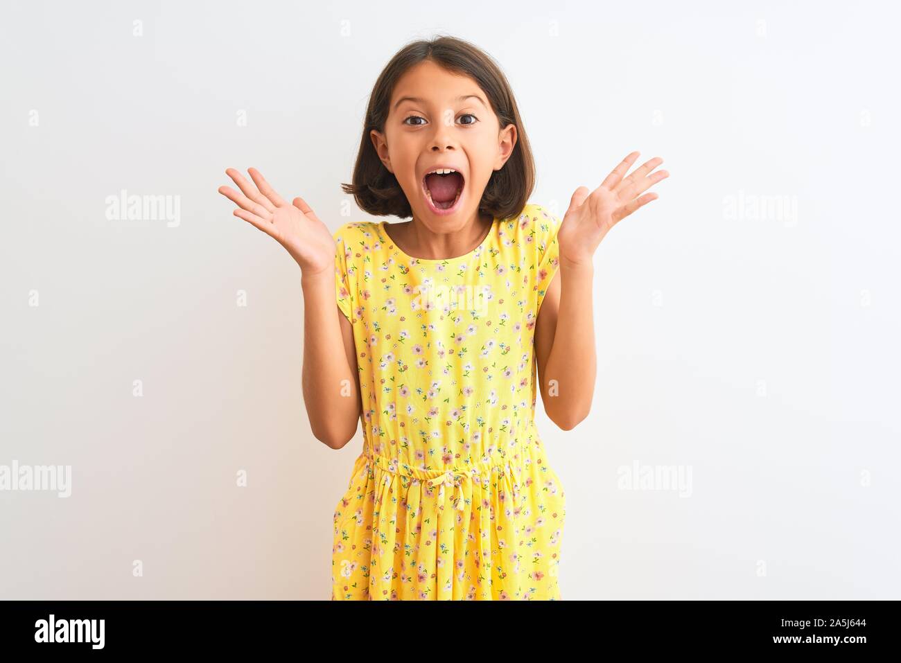 Young beautiful child girl wearing yellow floral dress standing over ...