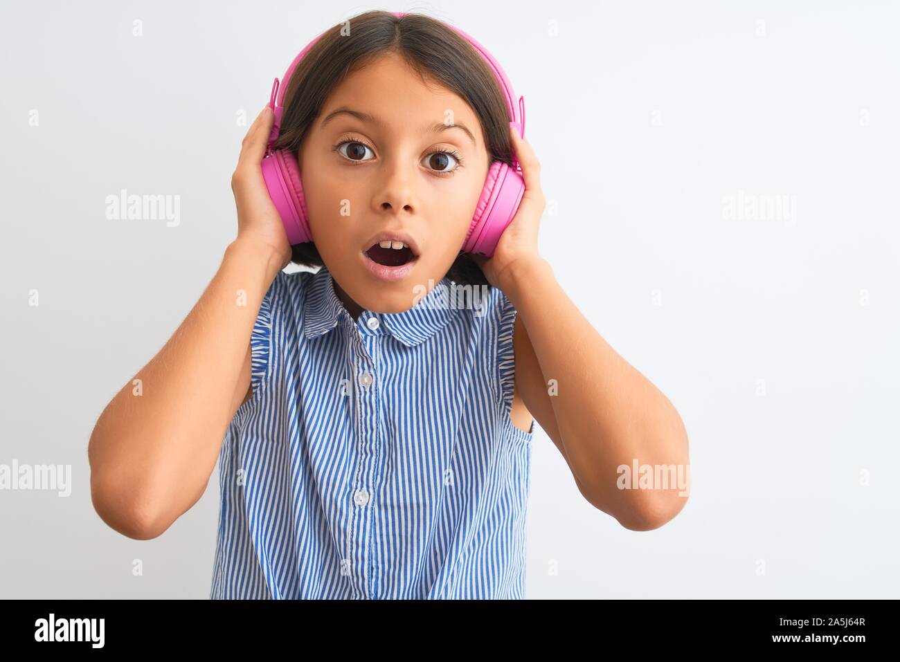 Beautiful child girl listening to music using headphones over isolated ...