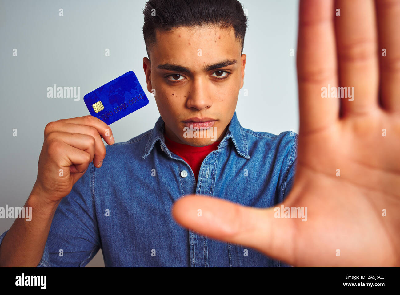 Young brazilian customer man holding credit card standing over isolated ...