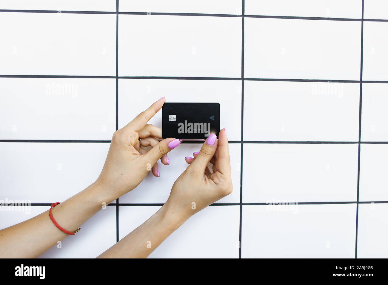Hands holding credit card in white tile wall background Stock Photo - Alamy