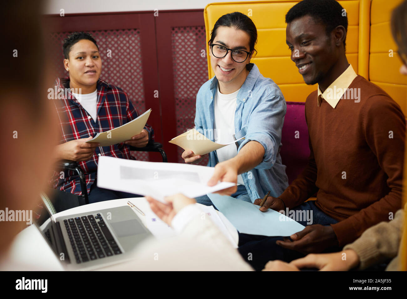Multi-ethnic group of cheerful students sharing notes while discussing ...