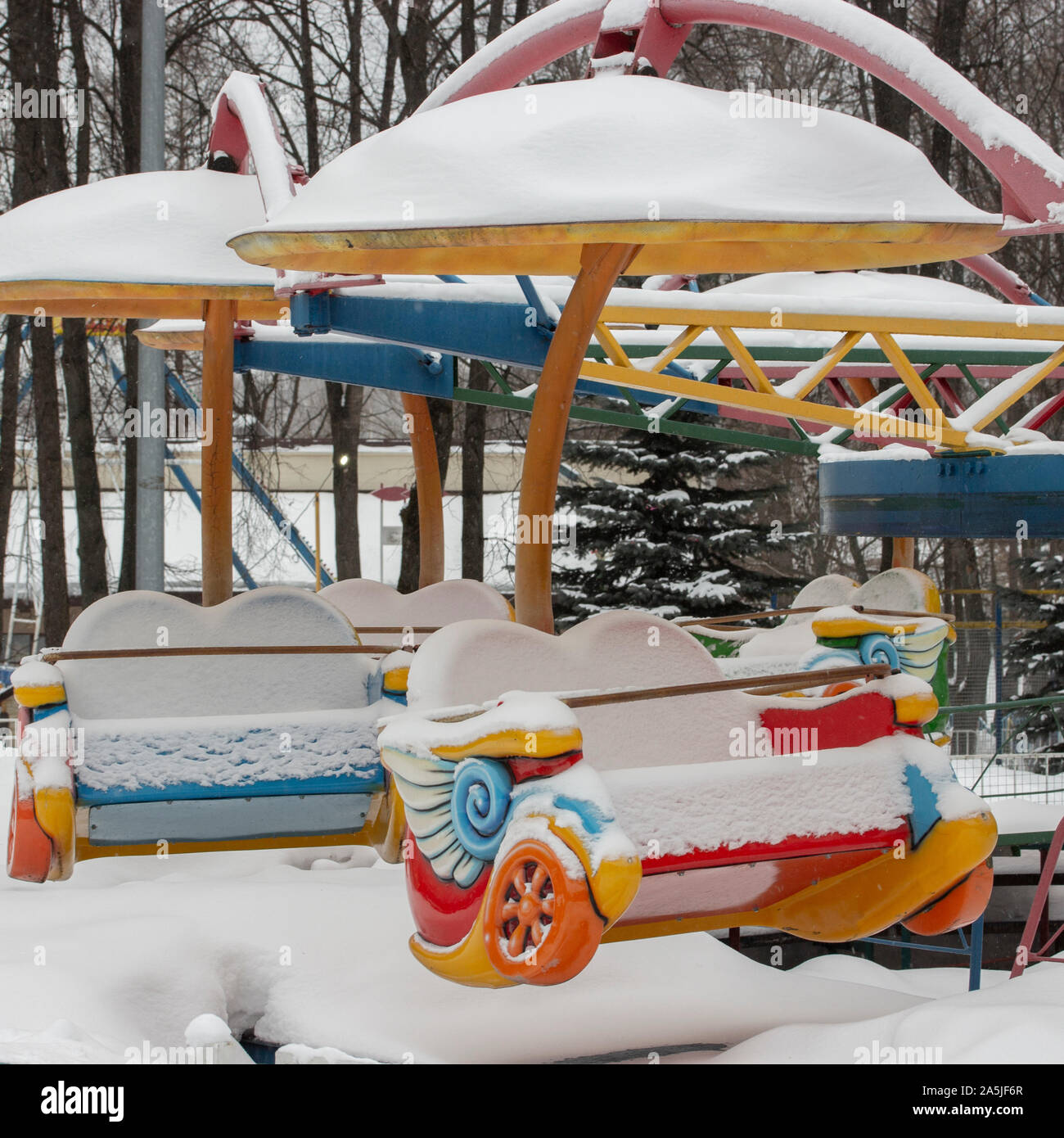 Swing carousel seat in the snow, bright multi-colored attraction empty ...