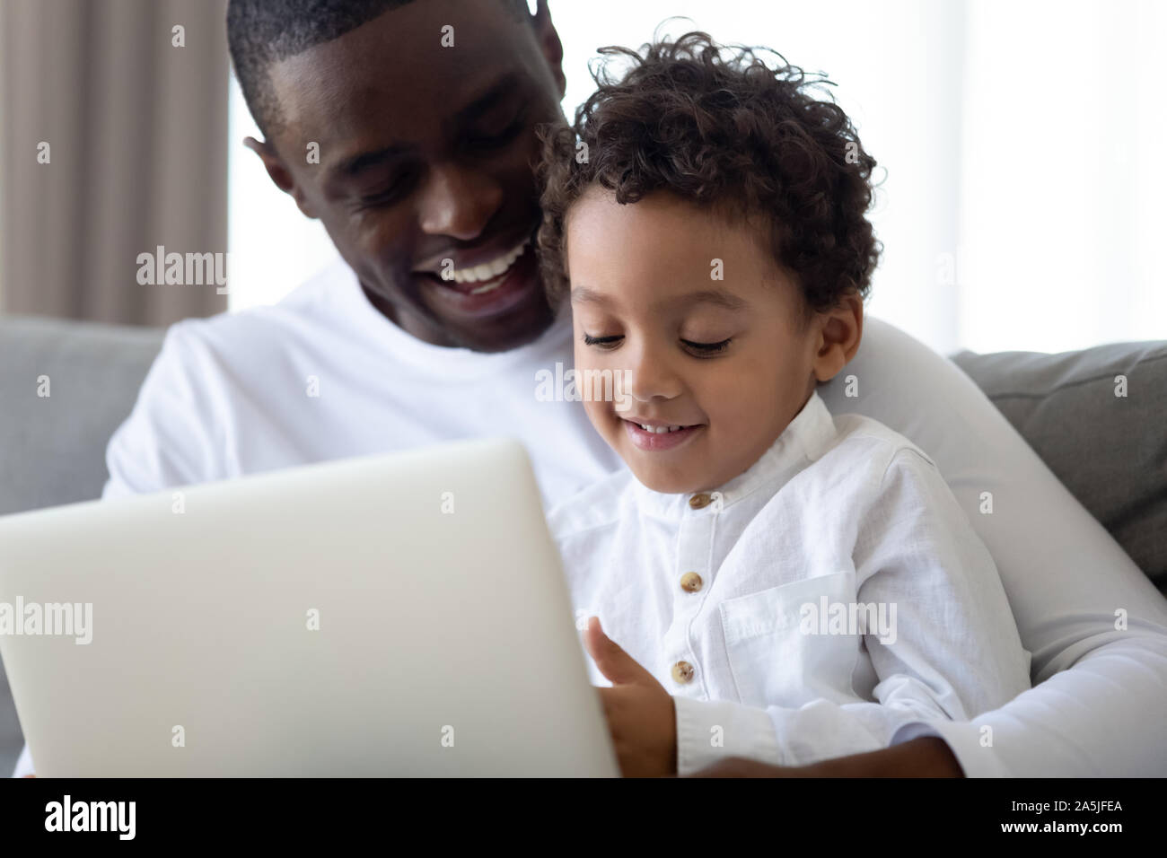 Loving dad relax using laptop with little biracial son Stock Photo - Alamy