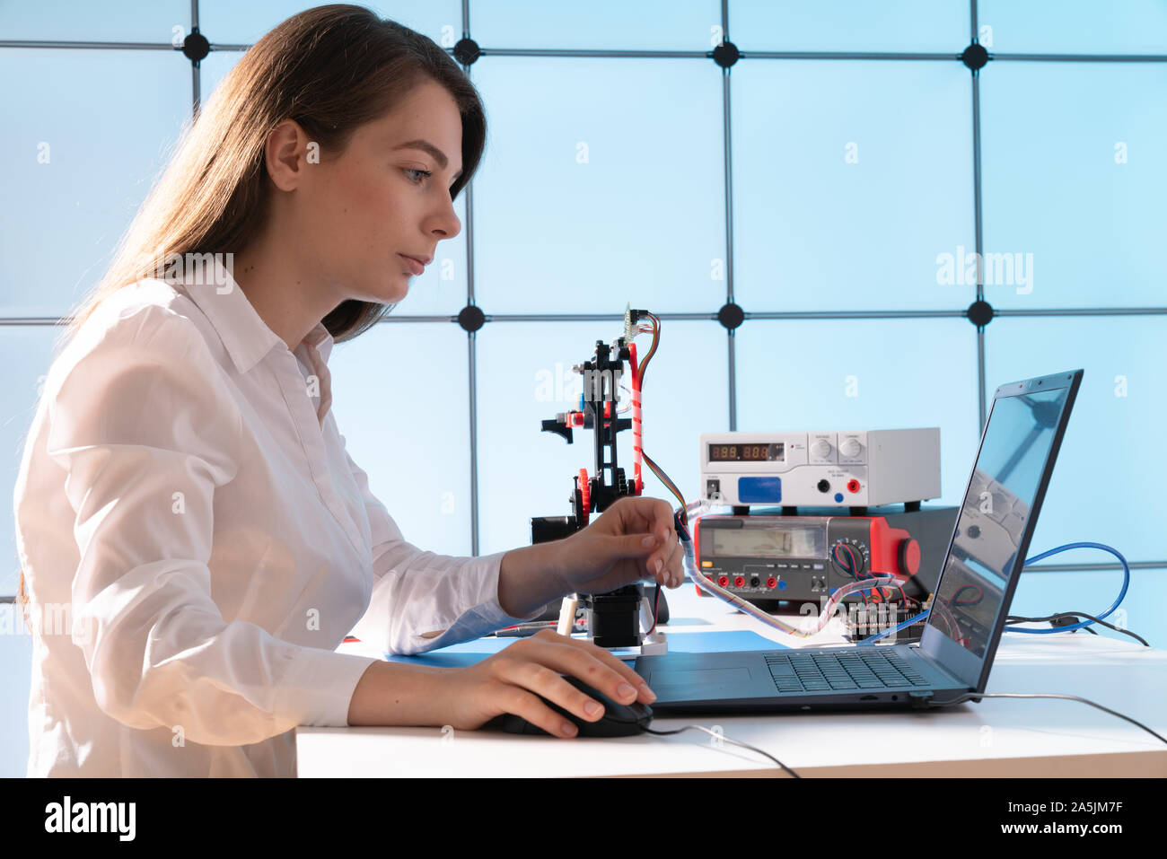 A young woman writes an algorithm for the robot arm. Science Research ...