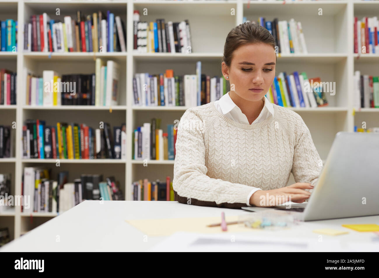 Portrait of female student using laptop while studying in college ...
