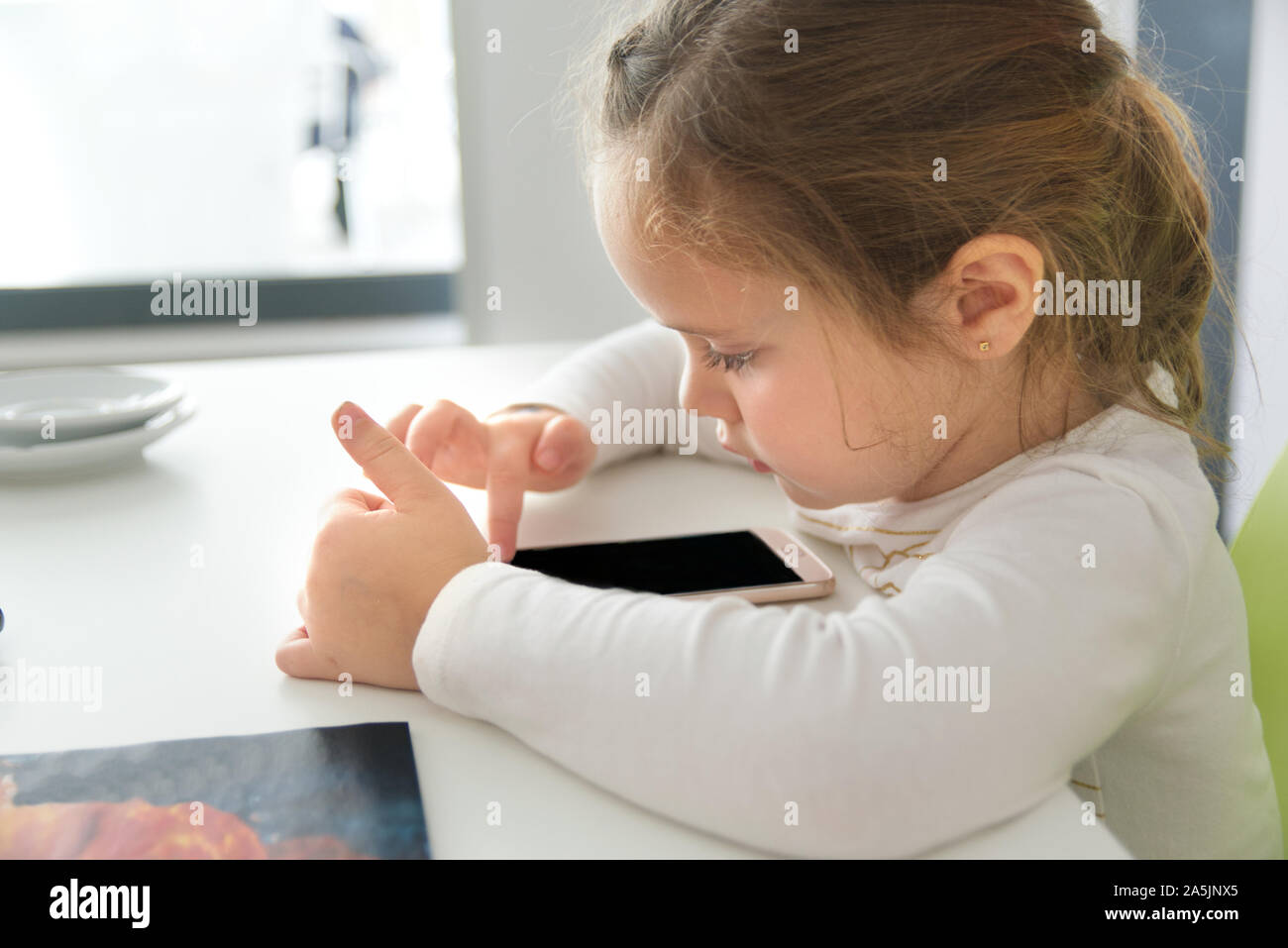 Young little girl using a mobile smart phone application software for ...