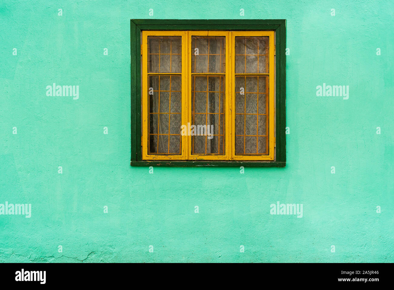 Old yellow window with bars on blue wall Stock Photo - Alamy