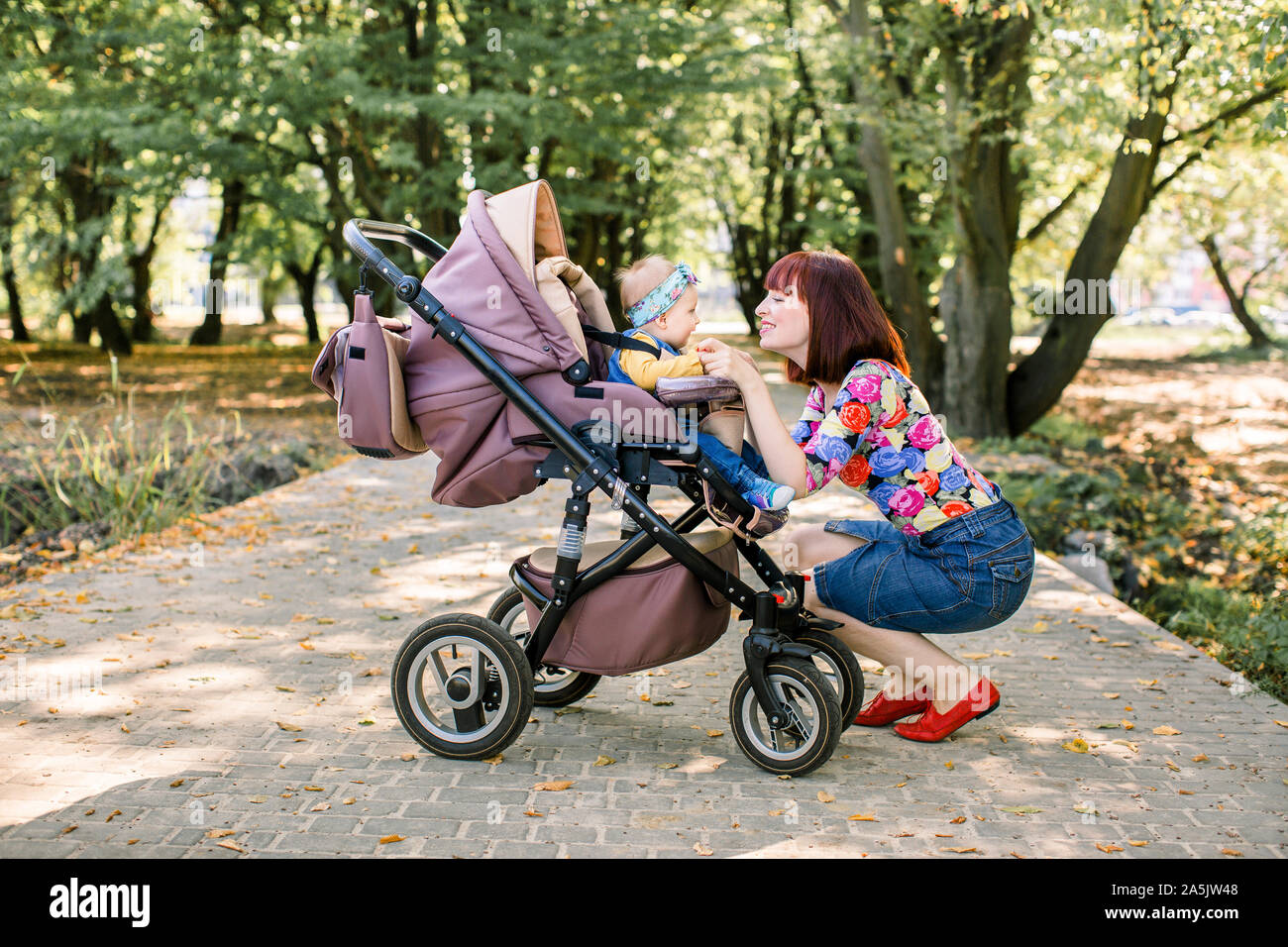 Young mother looking at her child in a baby stroller Stock Photo - Alamy