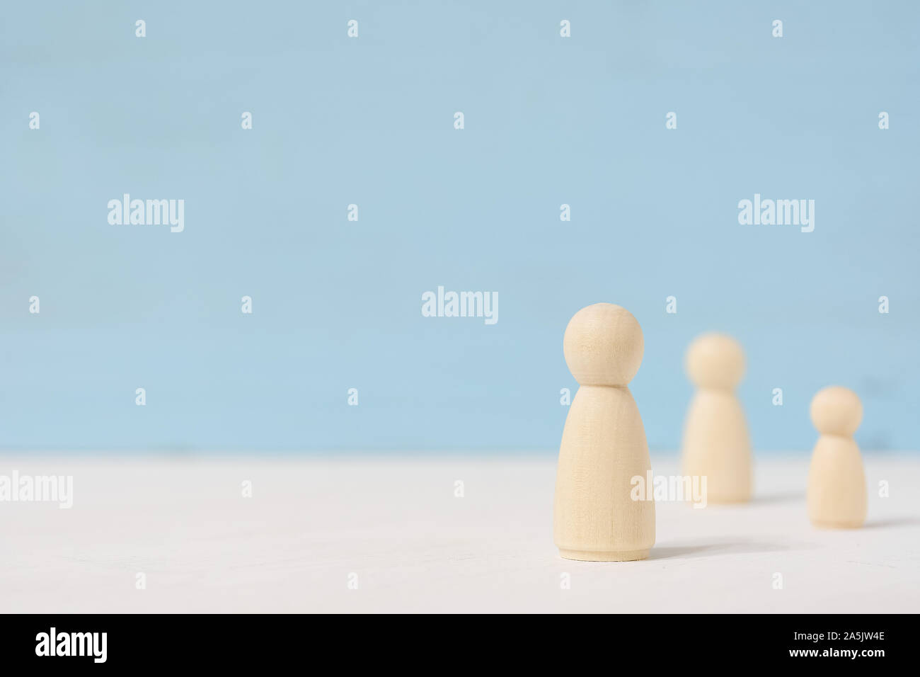 Abstract three faceless wooden toy figures stand apart from each other ...