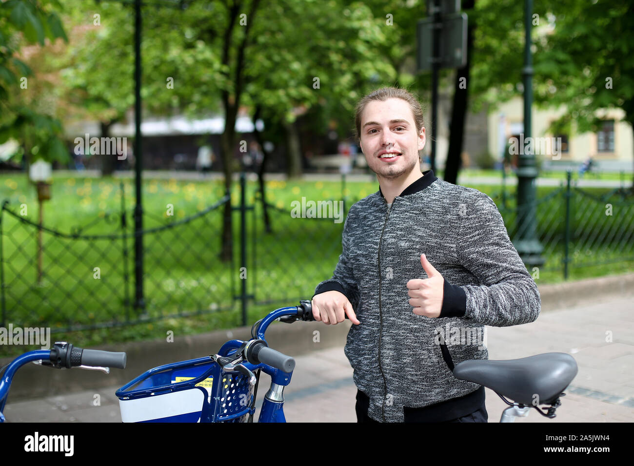 Young boy standing with hired bike near park with green trees Stock ...