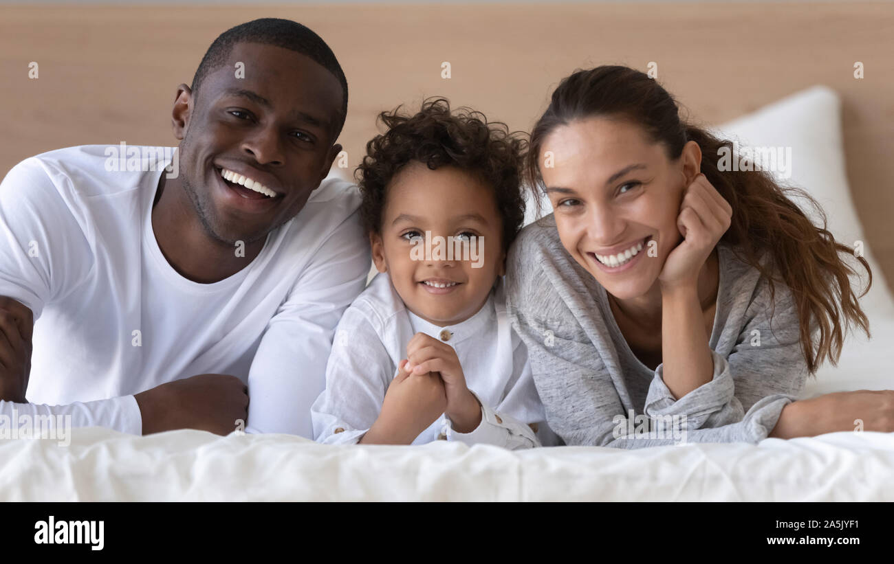 Portrait of happy multiracial family of three posing in bedroom Stock ...