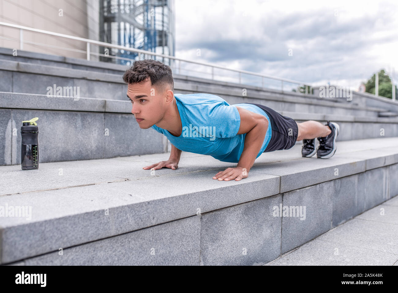 male athlete pushing up, in summer in city, background is steps. Active ...