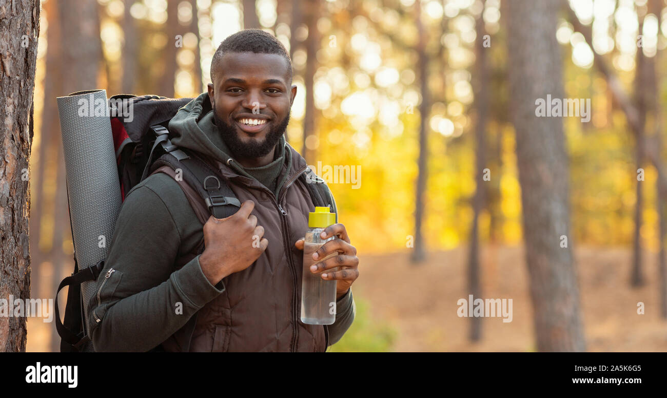 Happy guy with backpack smiling over forest background Stock Photo - Alamy