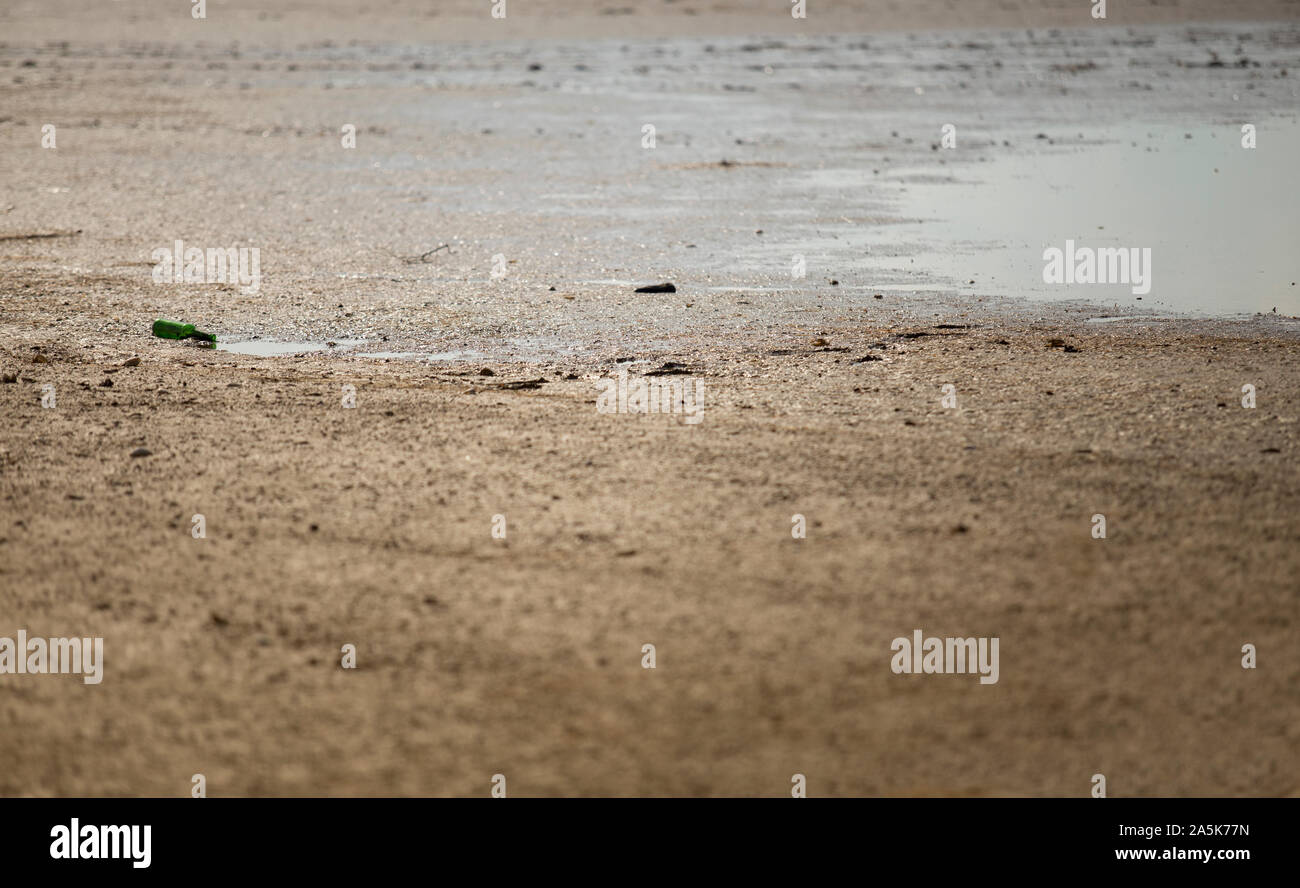 Dirty sandy beach polluted with glass bottles Stock Photo - Alamy