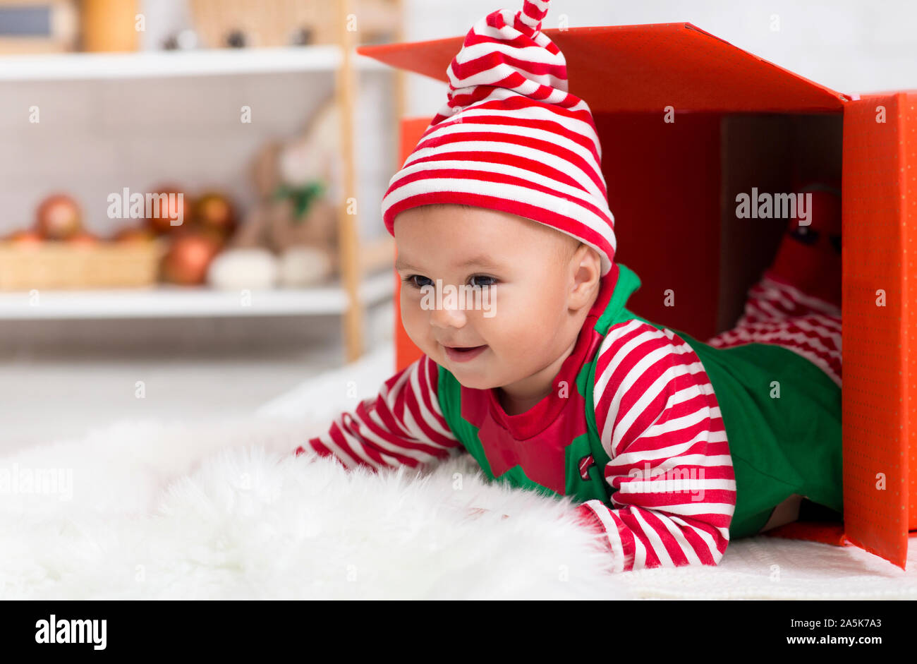 Adorable baby elf crawling out of gift box Stock Photo - Alamy