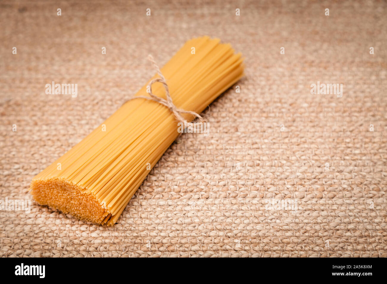 Italian spaghetti pasta tied in bunch by craft rope lying on natural ...