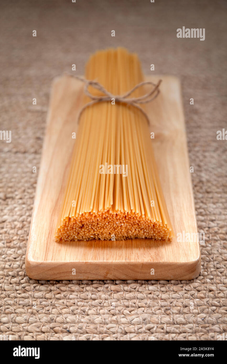 Italian spaghetti pasta tied in bunch by craft rope lying on natural ...