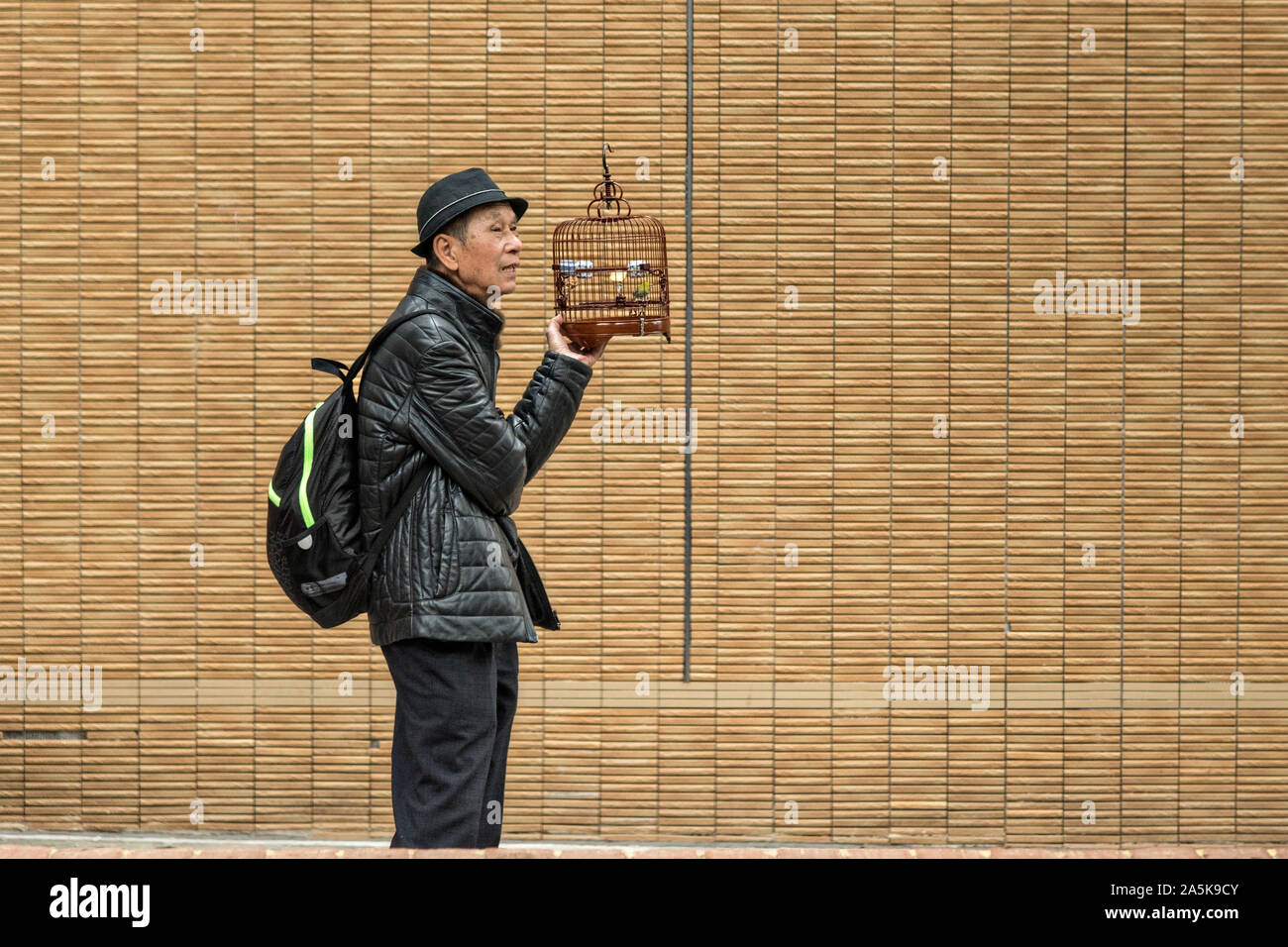A Chinese man smokes a cigarette holding his songbird cage at the Yuen ...
