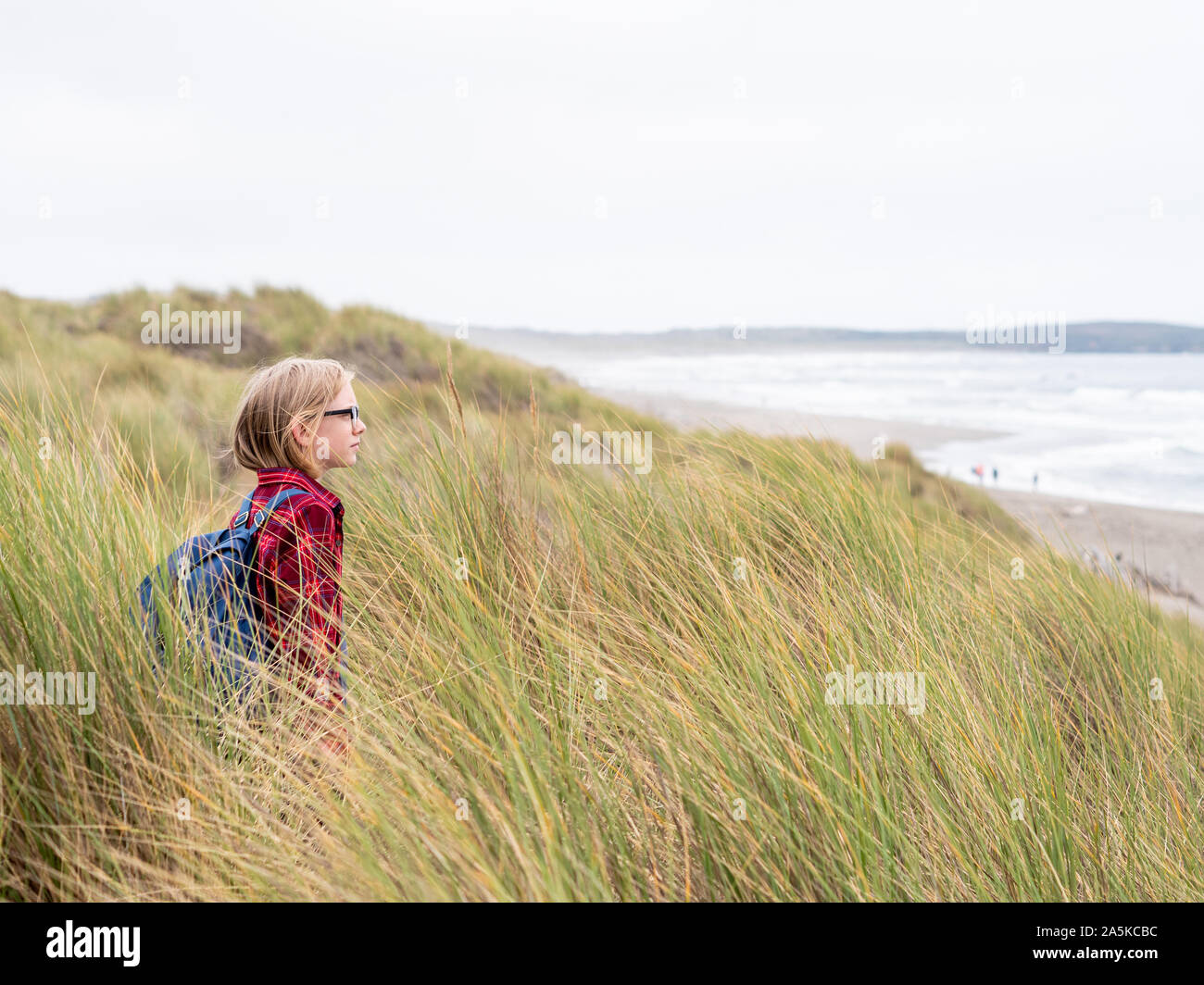 Profile view of young boy looking out over beach toward ocean Stock ...