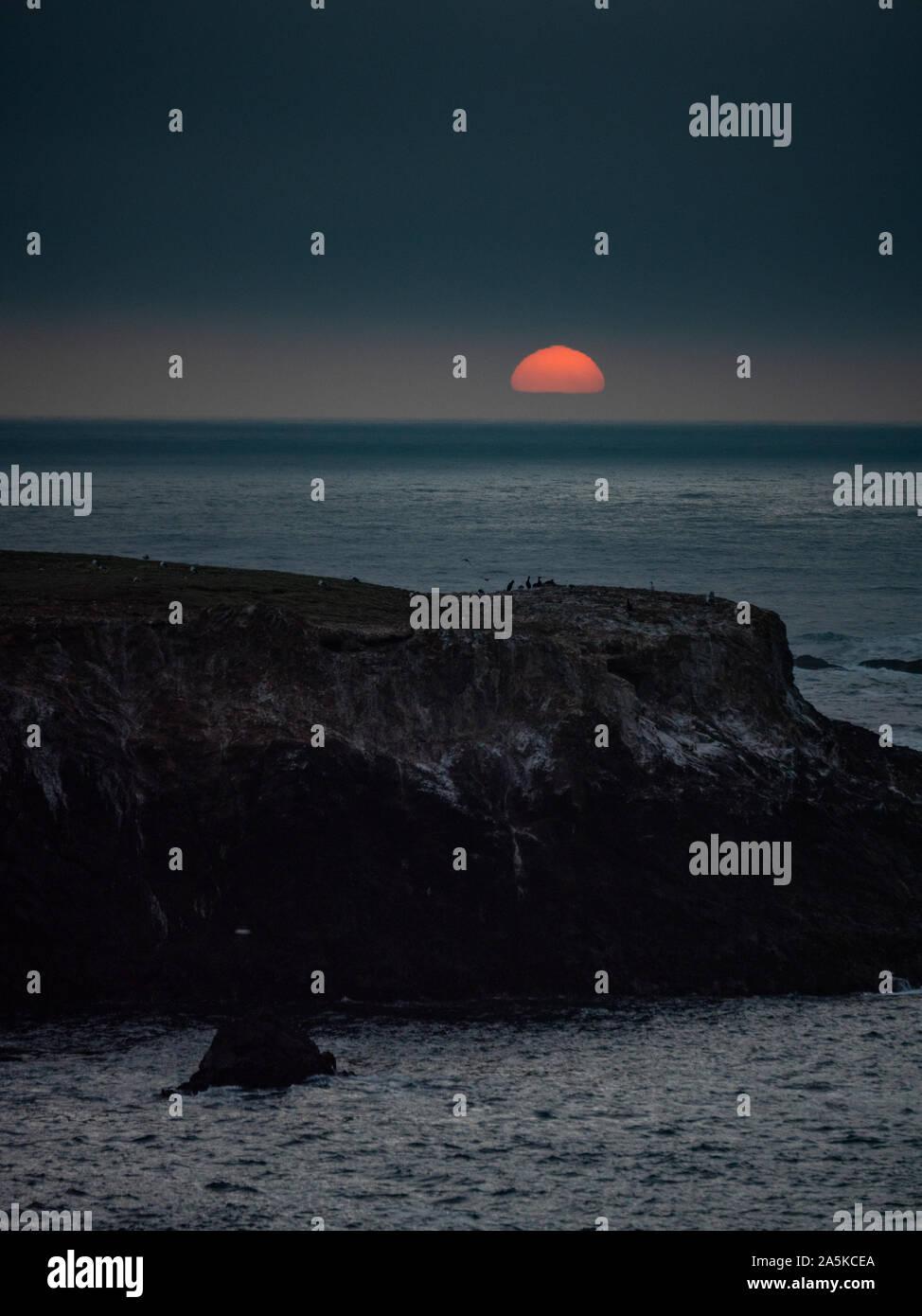 Warm Sun setting against cool blue ocean in Mendocino California Stock ...