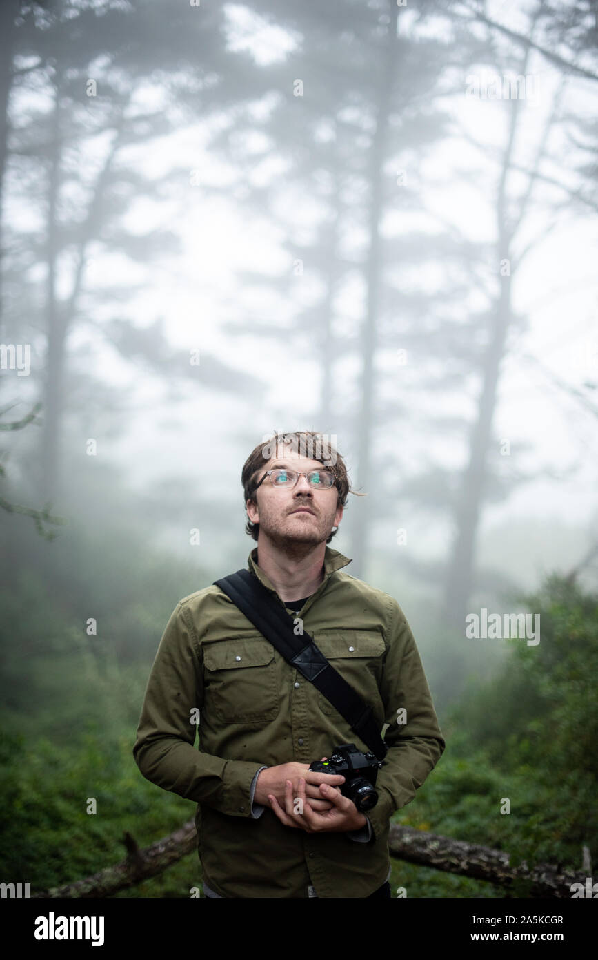 Portrait of photographer looking up into trees holding camera Stock ...