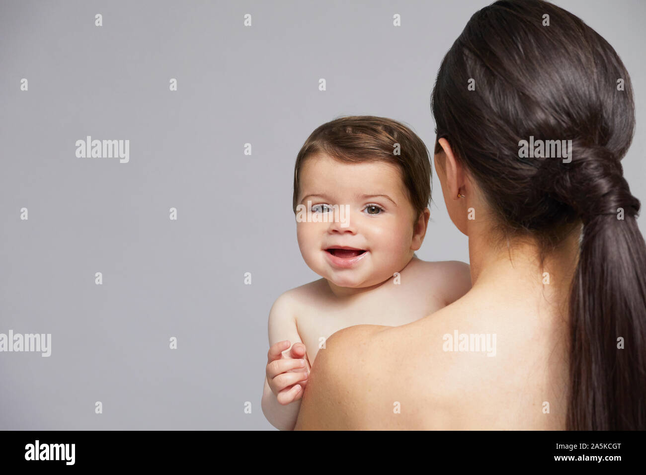 Baby looking over mother's shoulder Stock Photo - Alamy