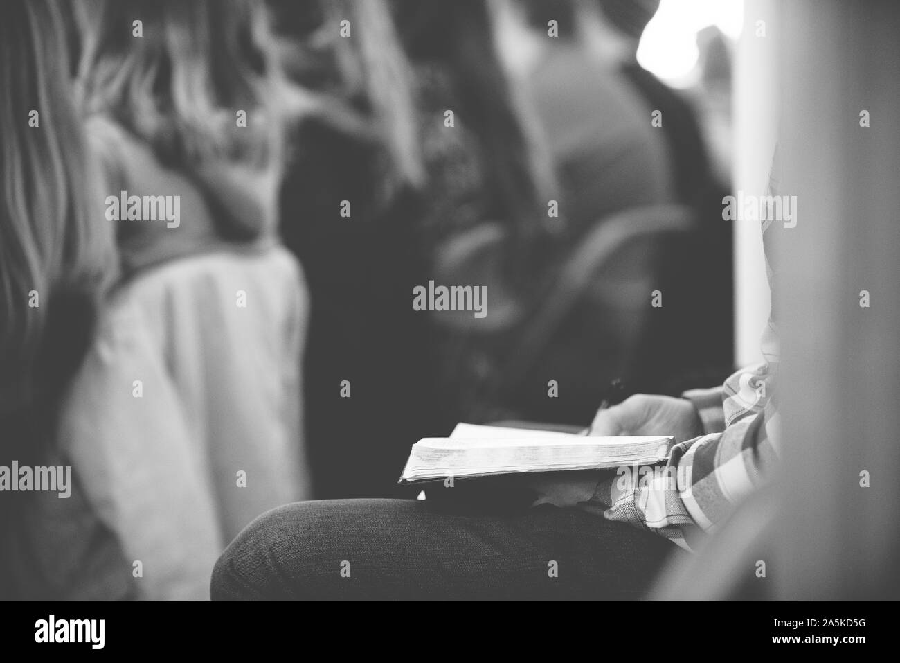 Black and white shot of a person reading a book with a blurred ...