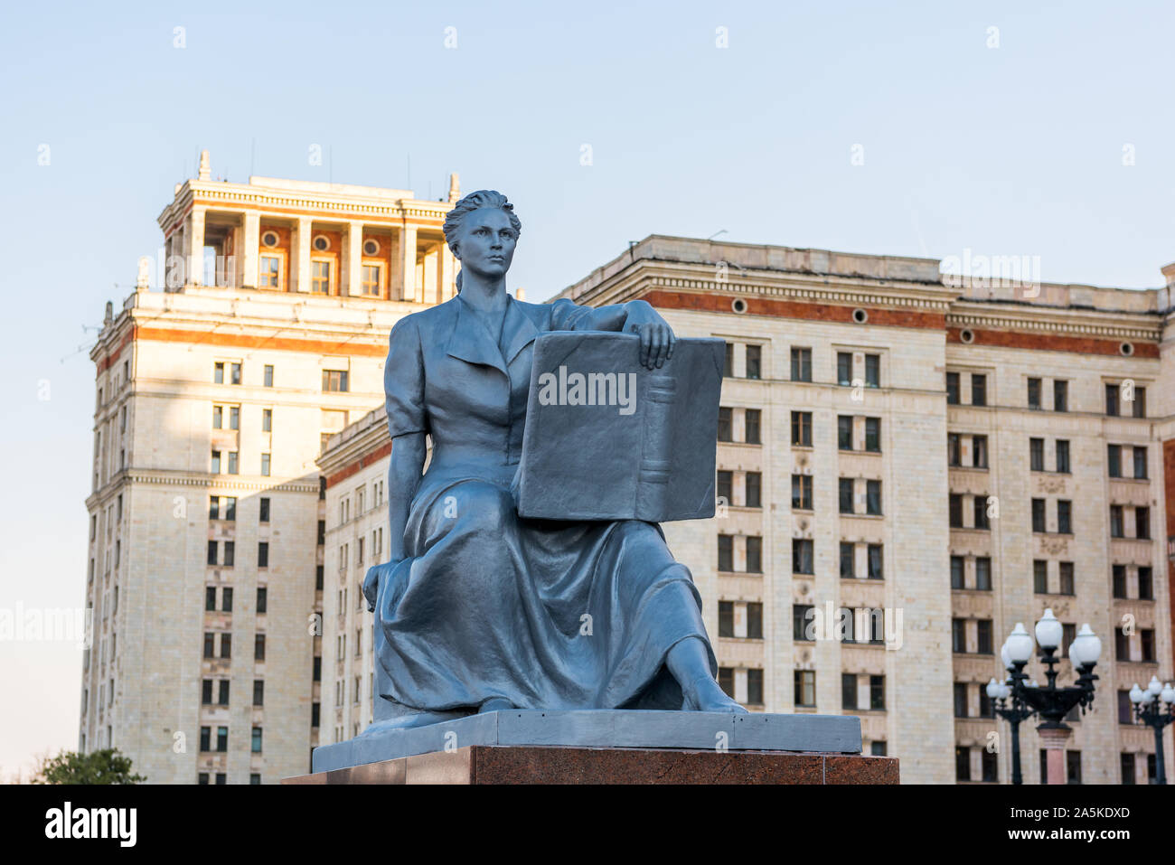 A statue of a female student with a book next to the entrance to the ...