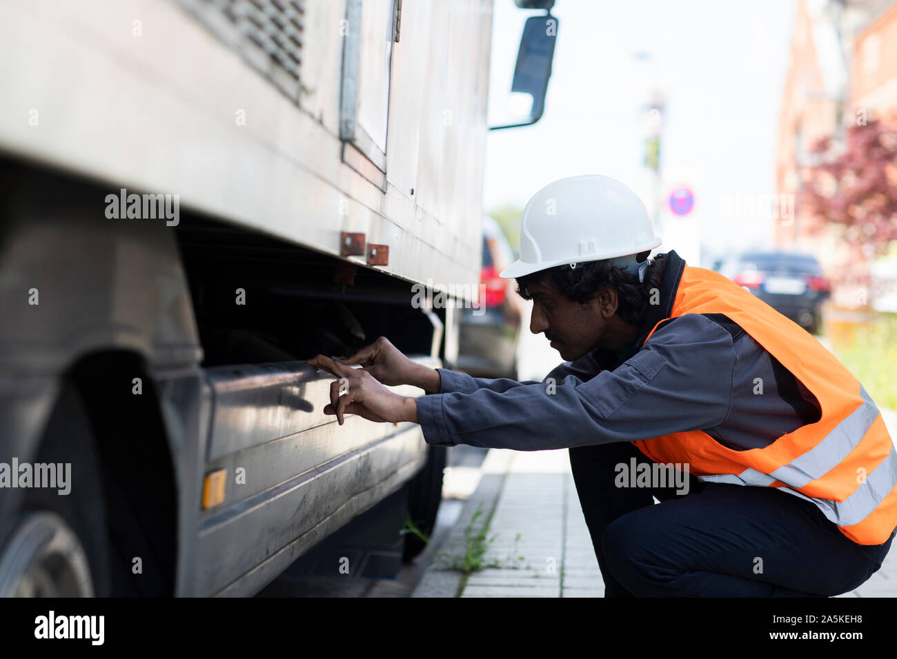 Male engineer looking beneath truck Stock Photo - Alamy