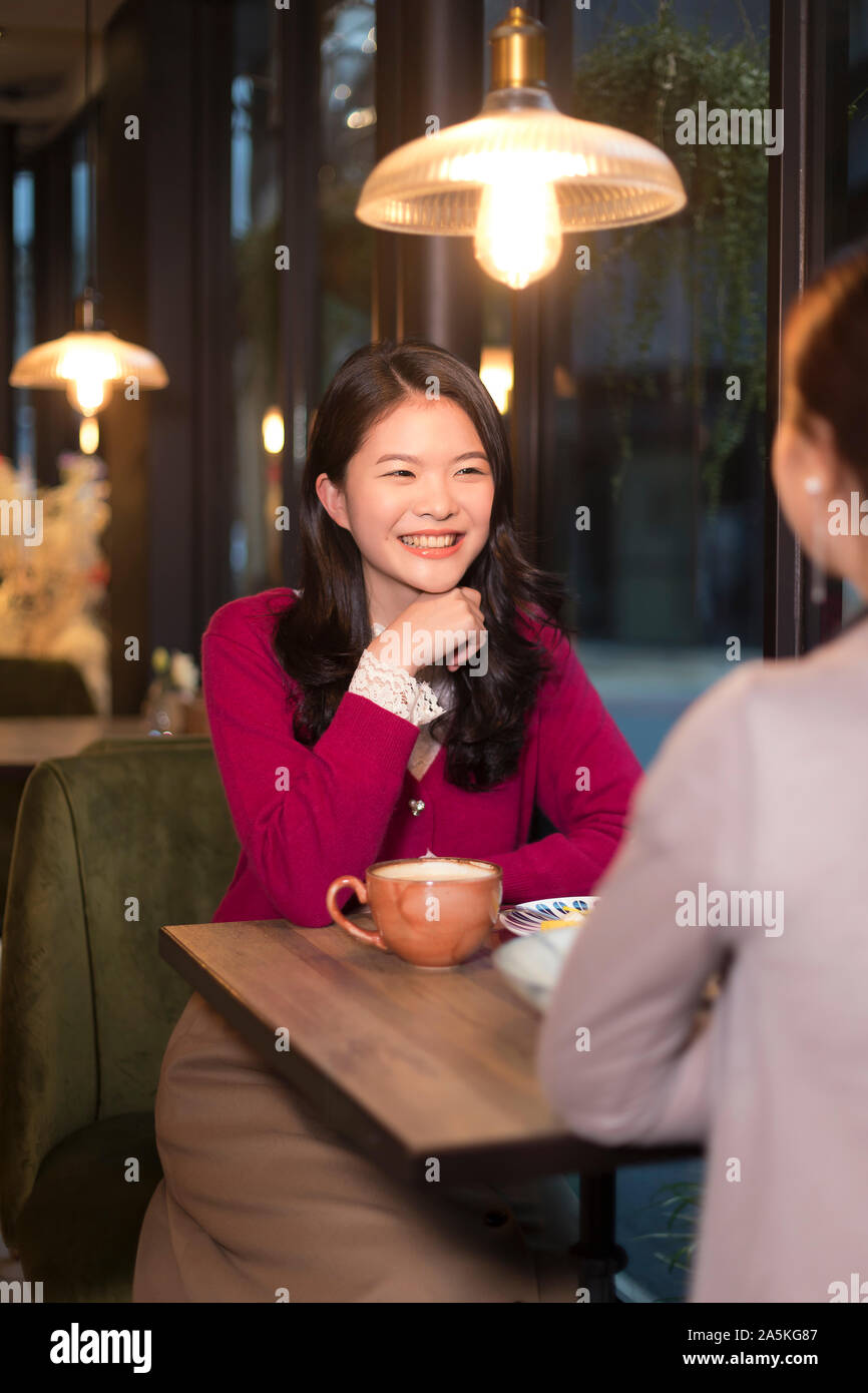 Two women having tea in restaurant by evening Stock Photo - Alamy