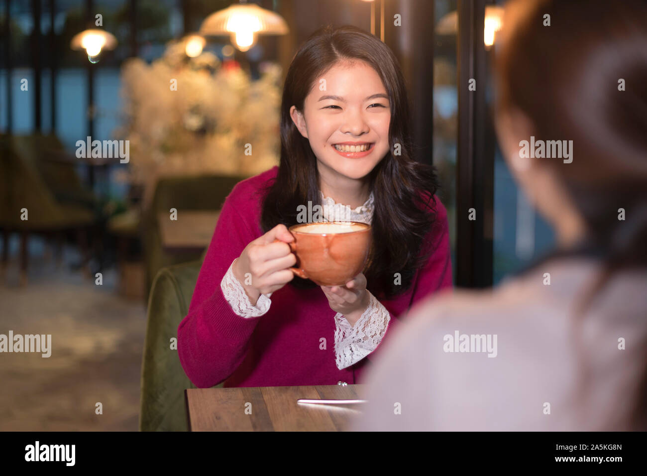 Two women having tea in restaurant by evening Stock Photo - Alamy