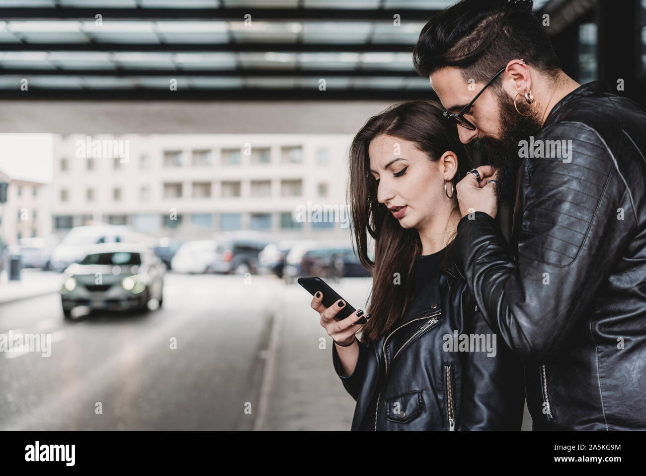 Couple using smartphone outside station Stock Photo - Alamy