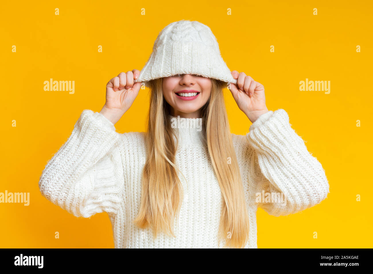Smiling woman pulling down white woollen hat Stock Photo - Alamy