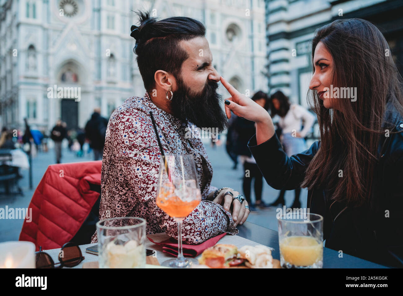 Woman playfully tapping nose of man in cafe, Santa Maria del Fiore ...