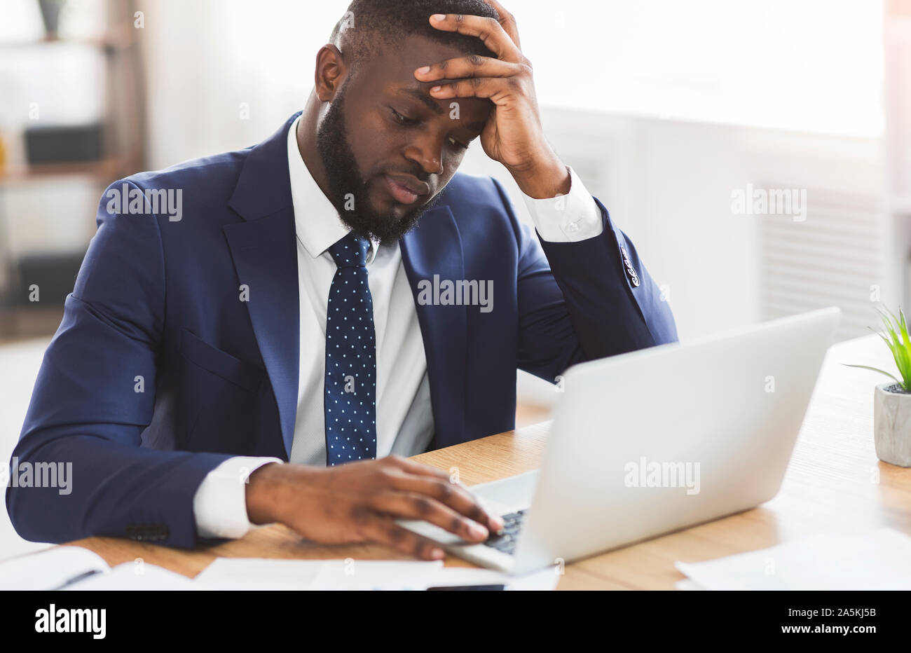 Depressed guy sitting in front of laptop at workplace Stock Photo - Alamy