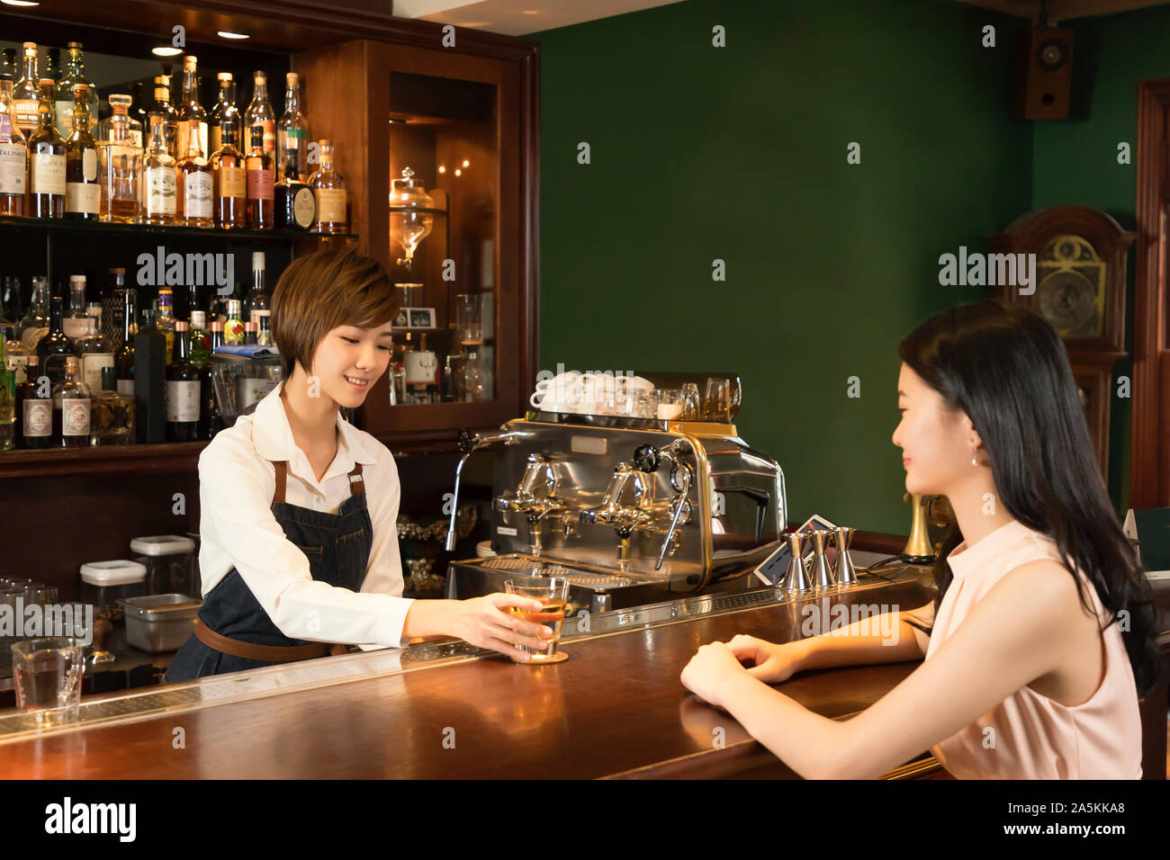 Female bartender serving drink to woman at bar counter Stock Photo - Alamy