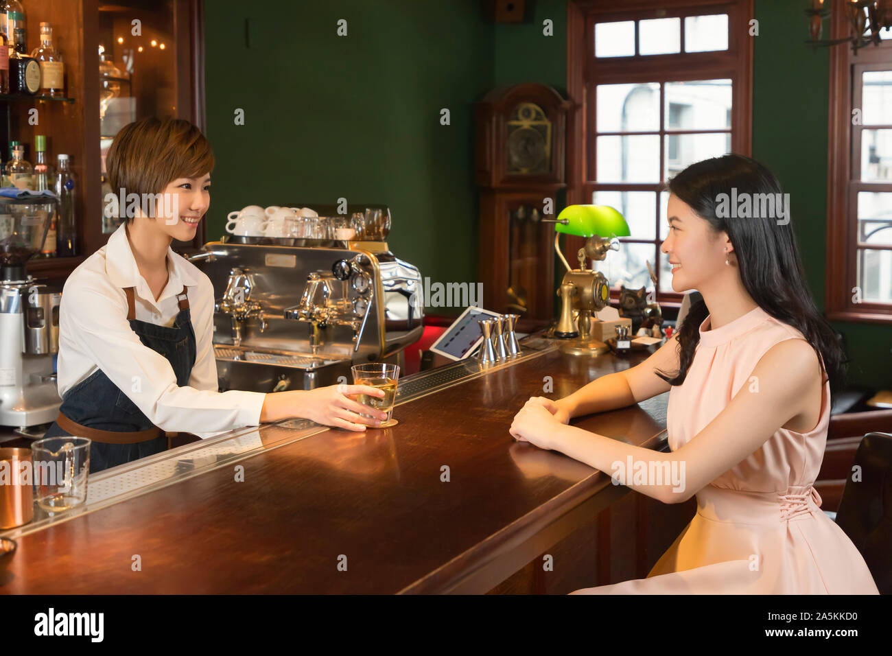 Female bartender serving drink to woman at bar counter Stock Photo - Alamy