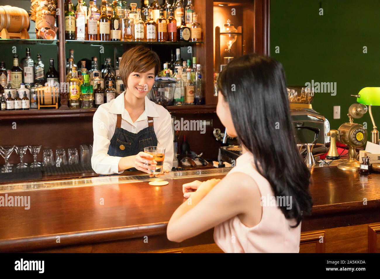 Female bartender serving drink to woman at bar counter Stock Photo - Alamy